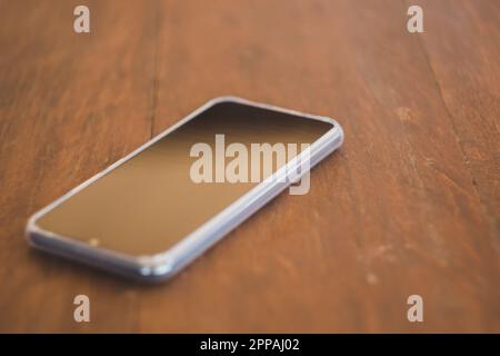 Black smart phones placed on a brown wood table Stock Photo - Alamy