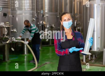 Woman vintner in mask checking wine process Stock Photo - Alamy