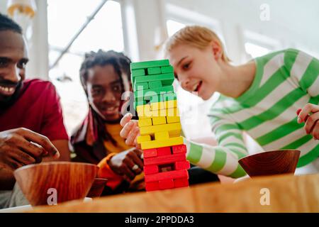 Friends playing block removal game looking at man showing smart phone ...