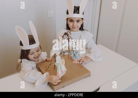 Two Children Wearing Bunny Ears when Pick Up painted Easter Egg Hunt In ...