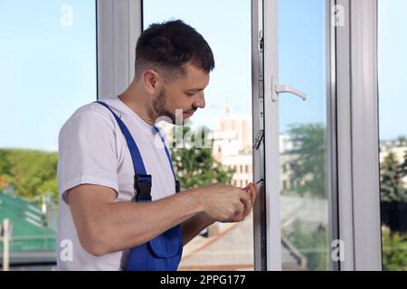 Worker adjusting installed window with screwdriver indoors Stock Photo ...