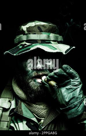 Bearded commando soldier with camouflage face paint, wearing a tactical ...