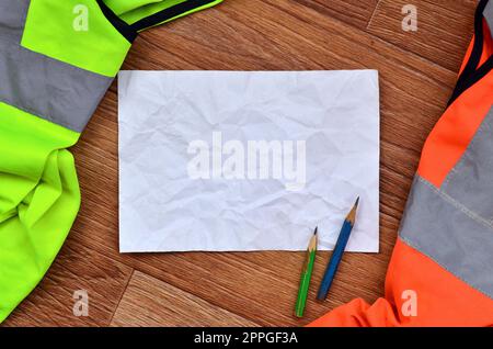 A crumpled sheet of paper with two pencils surrounded by green and ...