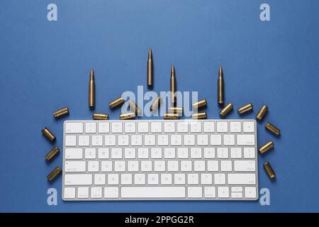 Bullets and computer keyboard on blue background, flat lay. Hybrid ...