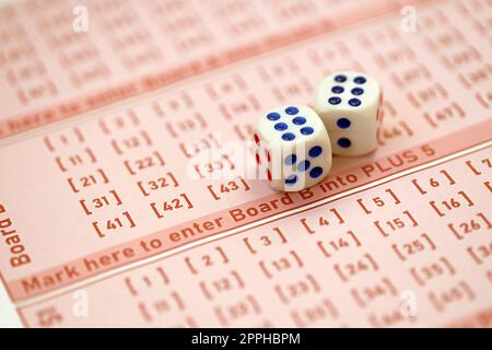 Dice cubes lies on pink gambling sheets with numbers for marking to ...