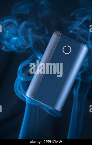 Black new GLO heating smoking device floats in puffs of white blue neon ...