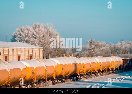 Snow covered tank-wagons with crude oil standing on the railway. View ...