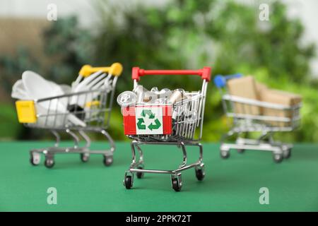 Shopping cart with recycling symbol full of garbage on light green ...