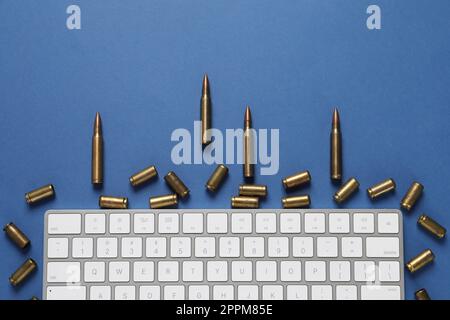 Bullets and computer keyboard on blue background, flat lay. Hybrid ...