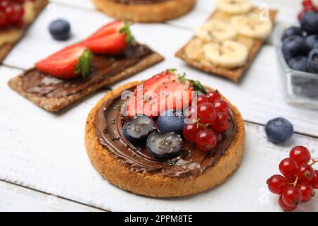 Fresh rye crispbreads and rusks with different toppings on light grey ...