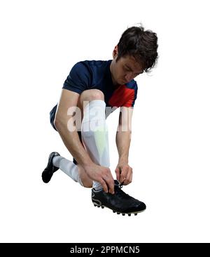 Soccer player ties his football shoes ready to play at the stadium ...