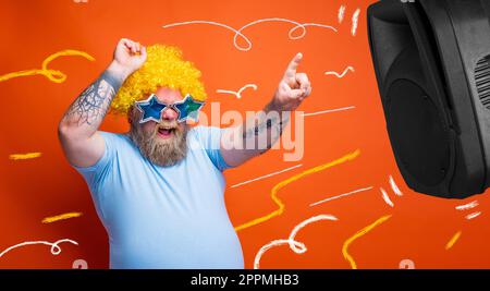 Fat amazed man with beard, tattoos and sunglasses combs himself with a ...