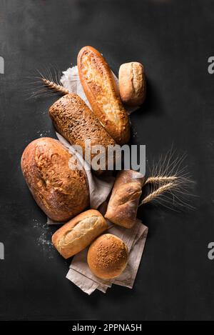 Assortment of various delicious freshly baked bread, on black concrete ...
