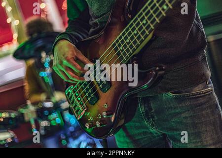 Close-up shot of a bassist's hands playing the bass guitar, fingers ...