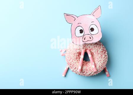Funny pig made with donut and straws on light blue background, flat lay ...