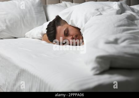 Handsome man sleeping under soft blanket in bed at home Stock Photo - Alamy
