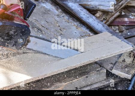 Cutting old wooden chipboards with electric chainsaw, splinters flying ...