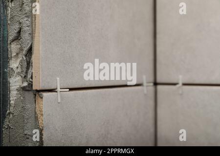 Stylish tiles with spacers on wall in room Stock Photo - Alamy