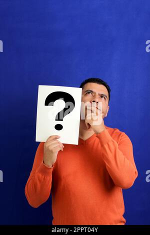 Latino brunette adult man shows a question mark, wonders, doubts ...
