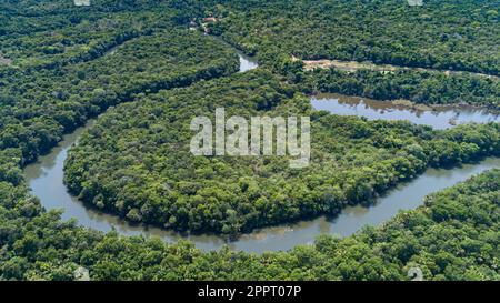 Aerial view of an meandering Amazon tributary river and buildings in ...