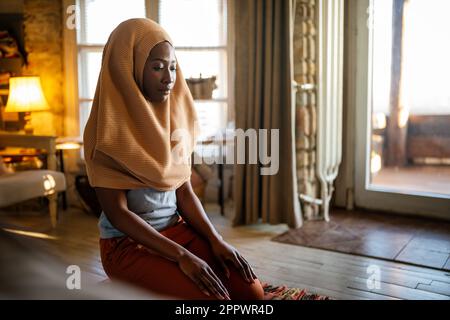 Young Muslim woman with Koran praying on yellow background Stock Photo ...