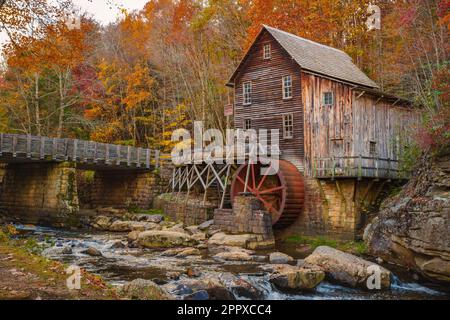 An old mill situated behind a waterfall surrounded by autumn foliage ...