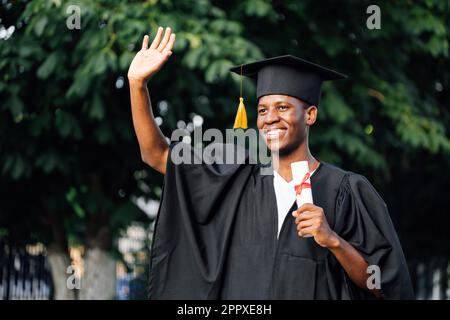 Rejoicing black guy graduate from university bouncing with happiness in ...