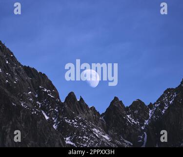 Moon rising, waxing gibbous phase, over snowcapped mountains in the ...