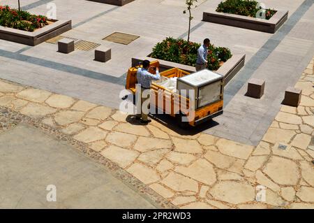 Three male operators unload the yellow electric car Stock Photo - Alamy