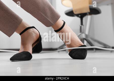 Woman tripping over cord in office, closeup Stock Photo - Alamy