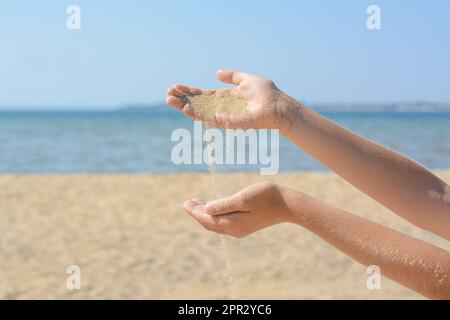 Child pouring sand from hands outdoors, closeup. Fleeting time concept ...
