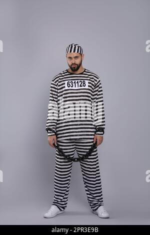 Prisoner in special uniform with chained hands on grey background Stock ...