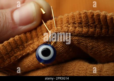 Woman pinning evil eye amulet on clothing, closeup Stock Photo - Alamy