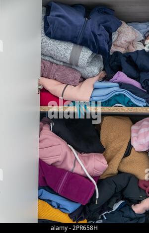 Chaotic wardrobe and sloppy closet shows many outfits of a woman with ...