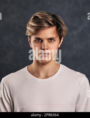 young man frowning on gray background. Human emotions Stock Photo - Alamy