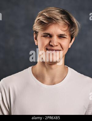 young man frowning on gray background. Human emotions Stock Photo - Alamy