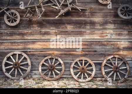 Wooden house wall and ancient wagon wheels, tools and stuff Stock Photo ...