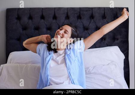 Rising to seize the day. young woman waking up from her sleep in bed at ...