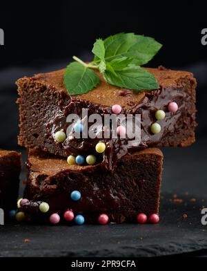 Baked pieces of chocolate brownie pie on a black table, on top of a ...