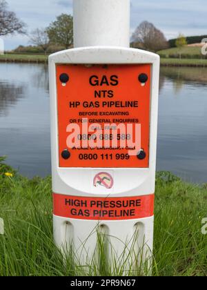 Gas pipeline marker post, warning of gas pipes below ground, on grass ...