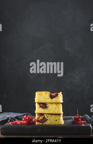 slices of biscuit plum cake on a white wooden board and fresh fruits ...