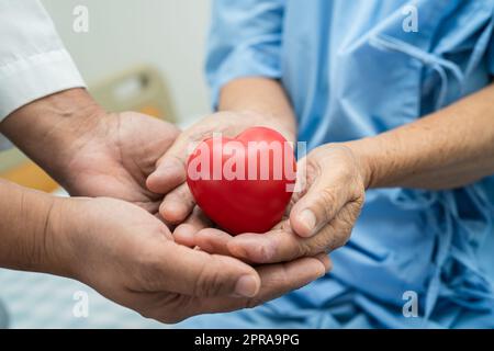 Doctor give red heart to Asian senior or elderly old lady woman patient ...