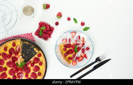 Round quiche with red strawberries and raspberries on a white table ...
