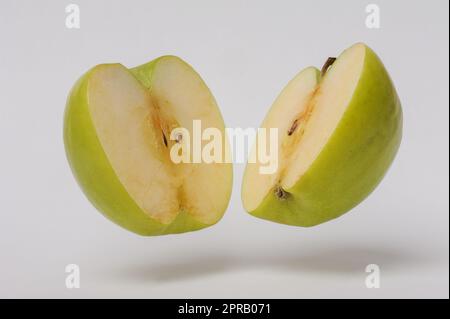 Green apple split in half on a white background, hovering Stock Photo ...