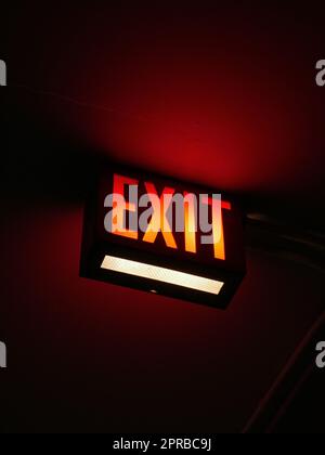 Well-lit Exit Sign in official colours. Glowing in orange and red. In ...