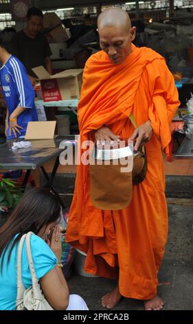 A Thai Buddhist monk blessing locals and receiving alms as part of a ...