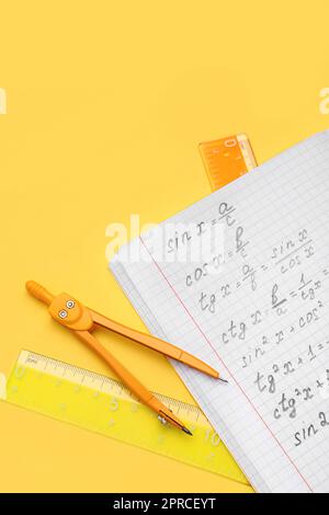 Copybook with maths formulas and stationery on yellow background Stock ...