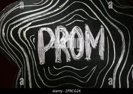 Chalkboard with word PROM on dark background with blurred lights ...
