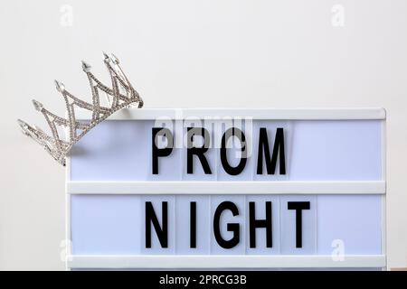 Board with text PROM NIGHT and crown on table against white background ...