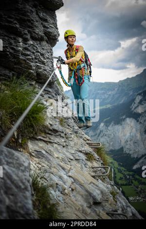 Pretty, female climber on a via ferrata - climbing on a rock in Swiss ...